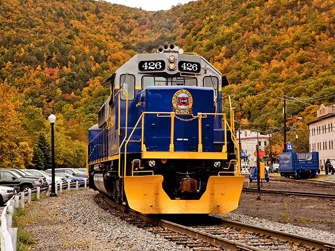 The iconic blue train of the Lehigh Gorge Scenic Railway winds through autumn’s vibrant tapestry—nature’s masterpiece in full display.