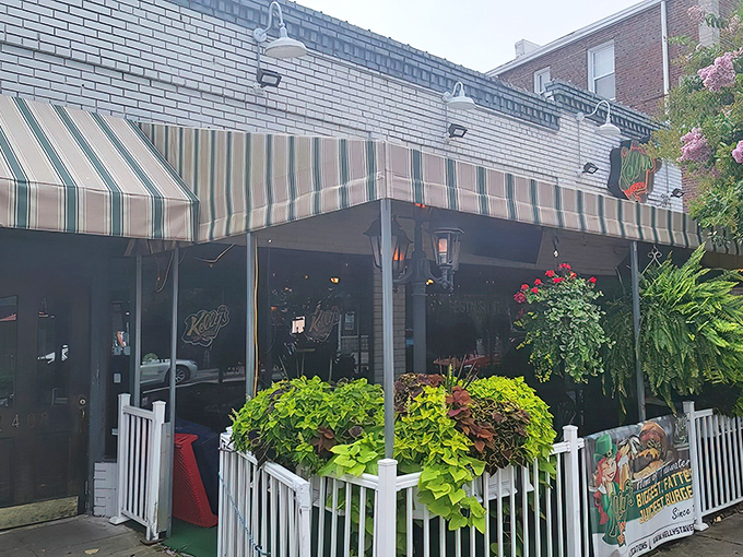 Kelly's welcoming exterior beckons with its classic striped awning and lush greenery. The patio seating offers a perfect perch for people-watching while savoring their famous fare.