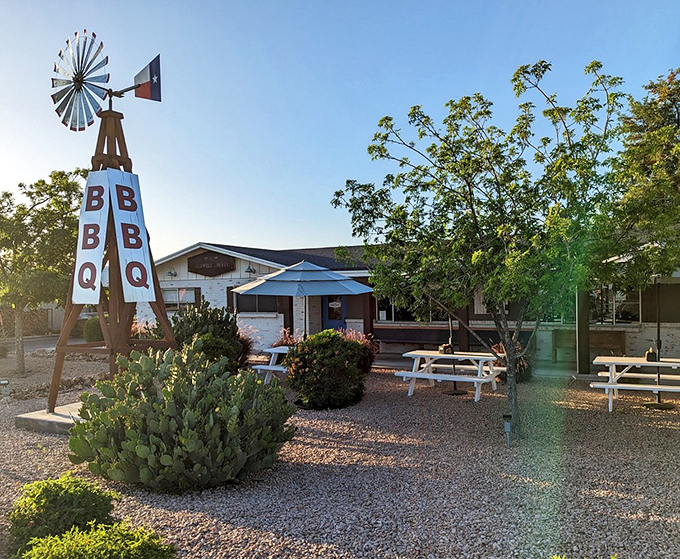 The Texas-style windmill stands sentinel outside Caldwell County BBQ, a desert oasis where smoke signals promise delicious things to come.