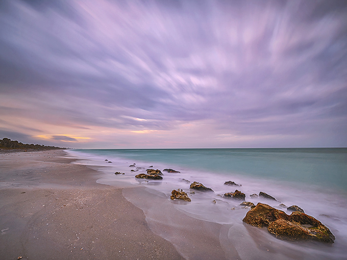 Mother Nature's watercolor masterpiece unfolds at Caspersen Beach, where turquoise waters meet pastel skies and time seems to stand perfectly still.