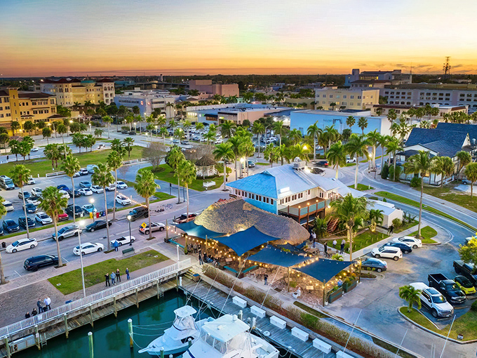 Sunset paints the sky gold over Fort Pierce Marina, where tiki-roofed restaurants promise seafood feasts and waterfront memories.
