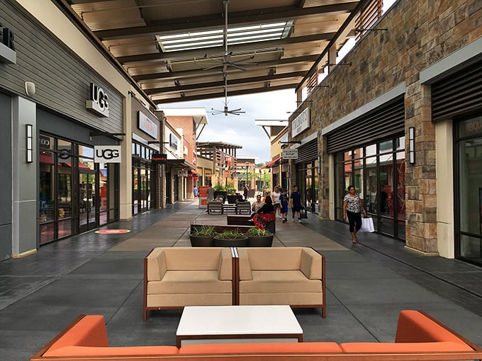 Twilight transforms Clarksburg Premium Outlets into a glowing retail paradise where shoppers drift between stores like treasure hunters on a mission.