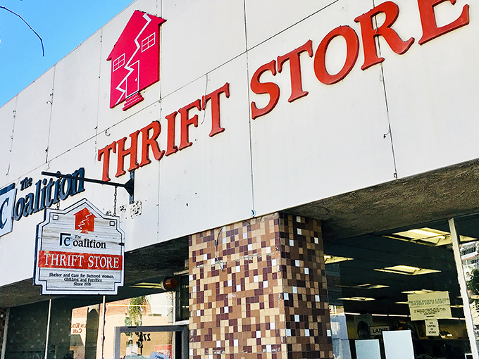 The iconic red house logo of Coalition Thrift Store beckons treasure hunters with a promise of adventures waiting inside those unassuming walls.