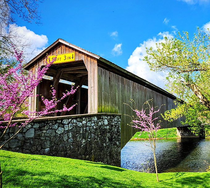 The timeless silhouette of Hunsecker's Mill Covered Bridge stands proudly against a blue Pennsylvania sky, its weathered boards telling stories of centuries past.
