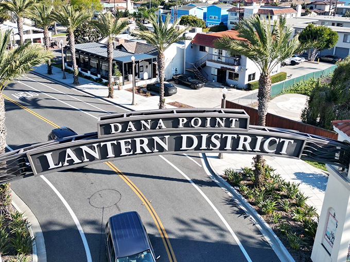 The iconic Dana Point Lantern District sign welcomes you to a slice of coastal paradise where palm trees sway and worries melt away faster than ice cream on a summer day.