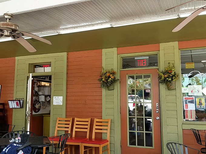 The salmon-colored exterior of Christo's Cafe welcomes you like a warm Florida morning, complete with lush greenery and shaded outdoor seating for those perfect Orlando days.