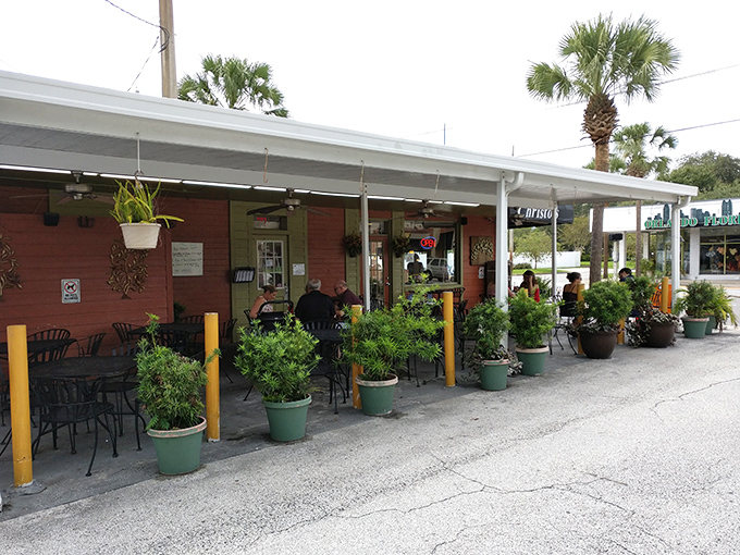 The coral-colored exterior of Christo's Café welcomes you with potted plants and outdoor seating—proof that culinary treasures often hide in unassuming packages.