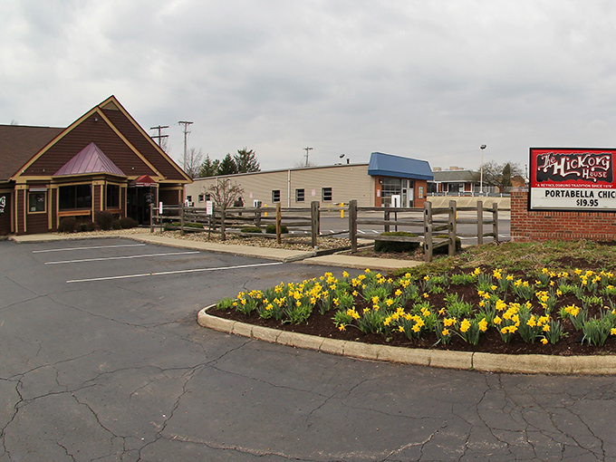 The welcoming exterior of Hickory House beckons with rustic charm, while spring daffodils add a cheerful touch to this barbecue haven.