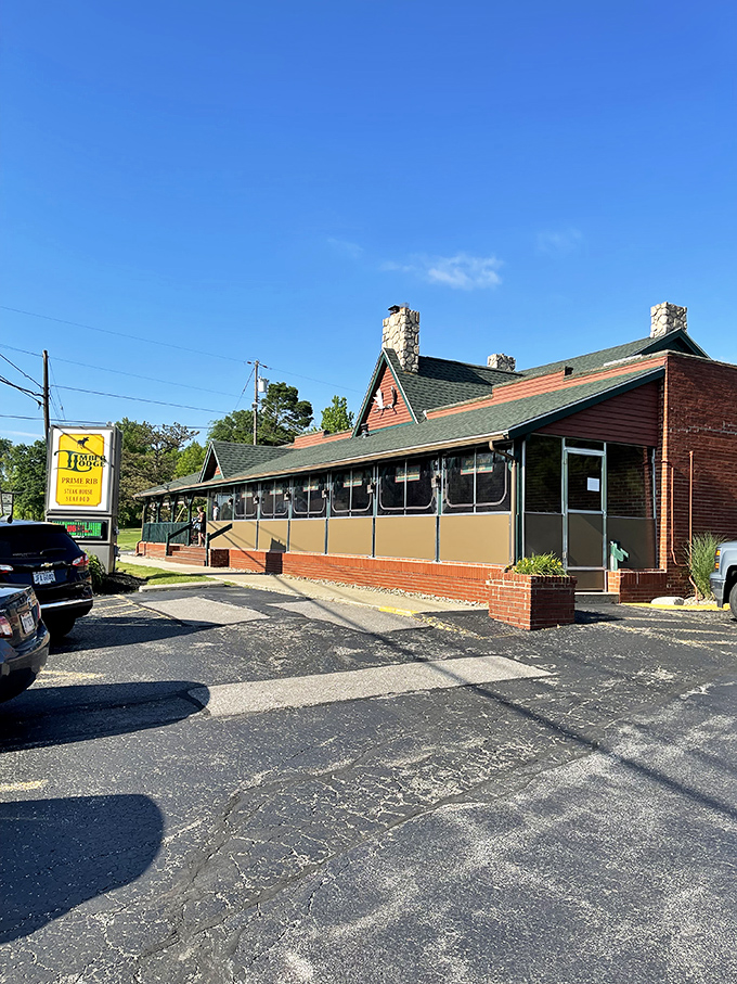 The rustic charm of Timber Lodge beckons from the roadside, its log cabin exterior and American flag promising a quintessentially Midwestern steakhouse experience.