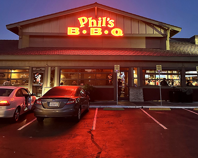 The neon glow of Phil's BBQ sign isn't just illumination&mdash;it's a beacon calling hungry souls home to barbecue paradise after sunset.