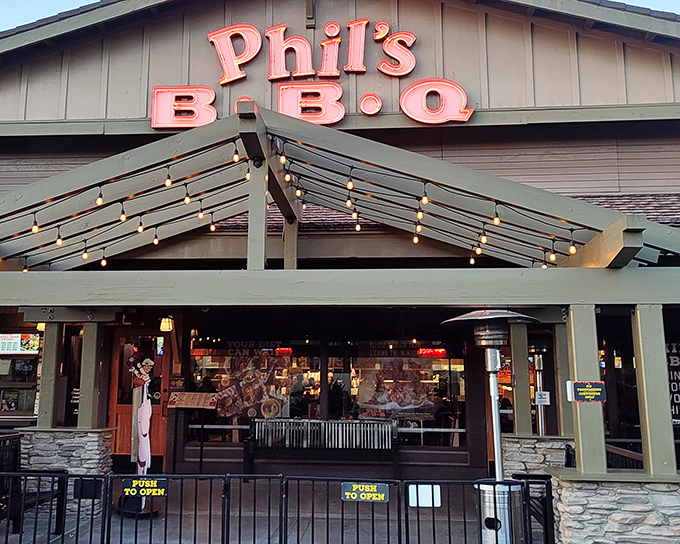 The neon glow of Phil's BBQ sign isn't just illumination&mdash;it's a beacon calling hungry souls home to barbecue paradise after sunset.