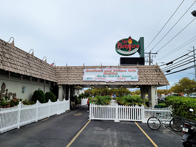 The iconic flame sign beckons hungry travelers like a coastal lighthouse, promising seafood treasures behind that rustic cedar shake exterior and charming white picket fence.