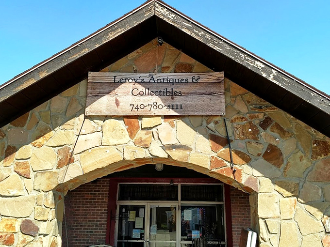 The stone facade of Leroy's Antiques & Collectibles stands like a humble guardian of treasures past, its wooden sign promising adventures in nostalgia beneath the Ohio sky.