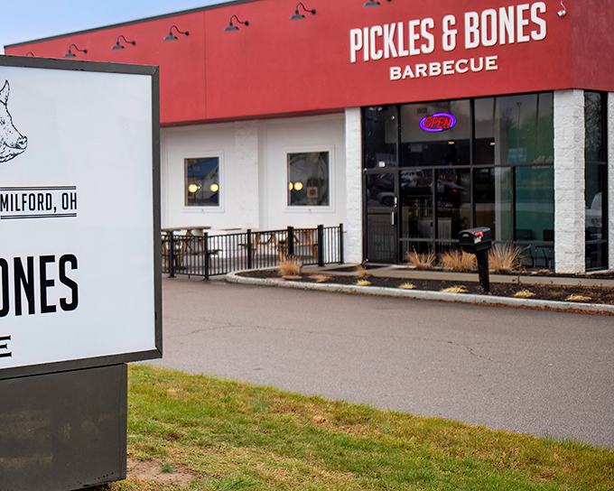The bright red exterior of Pickles & Bones stands like a barbecue beacon in Milford, promising smoky treasures within.