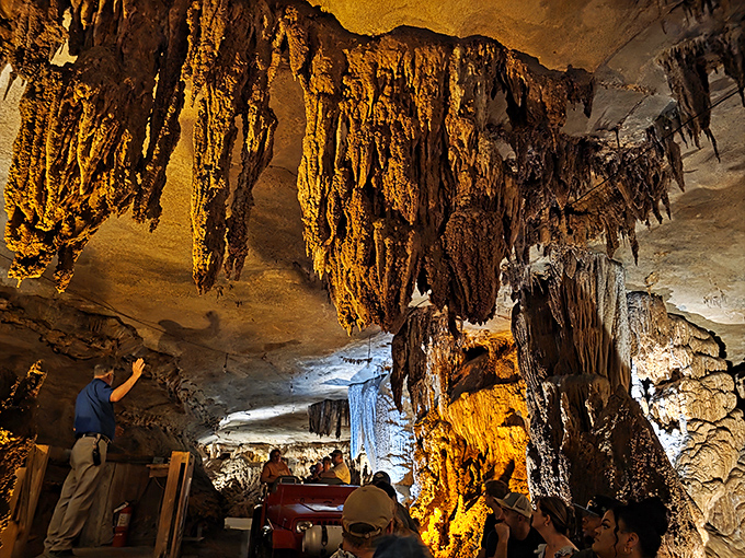 Behold nature's chandelier collection! These golden-hued stalactites dangle from the ceiling like prehistoric icicles while visitors enjoy the ride-through cave tour below. 