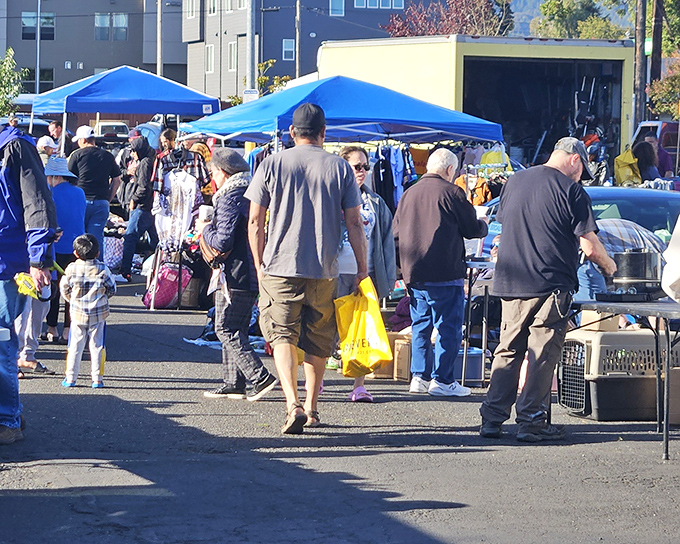 Shoppers navigate this asphalt bazaar with bags of possibility clutched in hopeful hands.