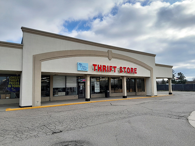 The bold red "THRIFT STORE" sign beckons like a lighthouse for bargain hunters. This unassuming exterior houses treasures waiting to be discovered.