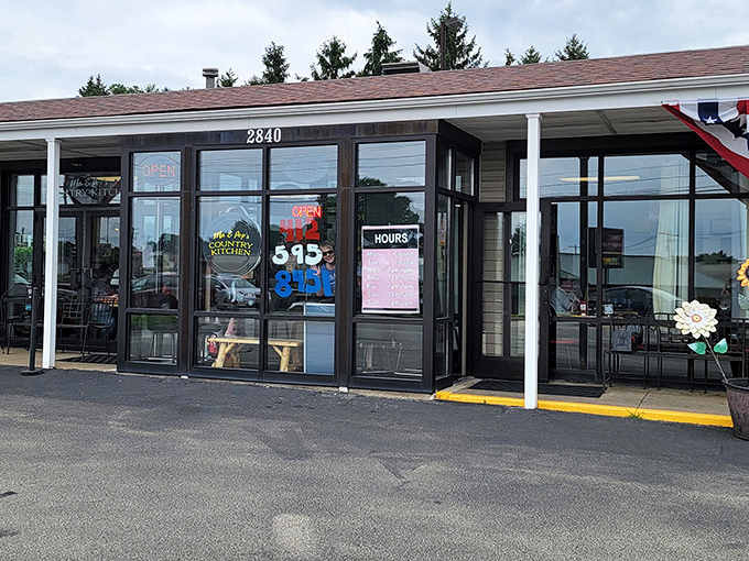 The unassuming exterior of Ma and Pop's Country Kitchen, where patriotic bunting and cheerful sunflowers hint at the warmth waiting inside.