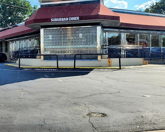 The burgundy awning and glass block windows of Suburban Diner stand as a beacon for hungry travelers. Classic roadside Americana at its finest.