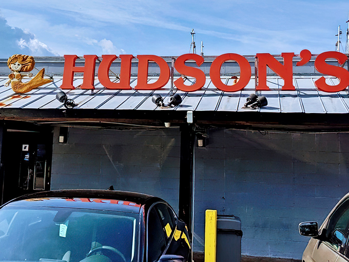 The iconic red Hudson's sign welcomes hungry seafood pilgrims like a maritime lighthouse guiding ships to delicious shores.