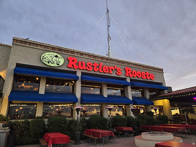 Rustler's Rooste stands proud against the Arizona sky, its blue awnings and glowing sign beckoning hungry travelers like a carnivorous oasis in the desert.