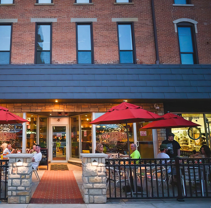 The historic brick façade of Six Hundred Downtown welcomes pizza pilgrims with its cheerful red umbrellas and inviting patio seating.