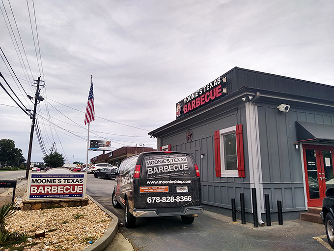 The unassuming exterior of Moonie's Texas BBQ stands like a smoke-scented beacon of hope for hungry travelers. That American flag isn't just decoration&mdash;it's a promise of patriotic flavor.