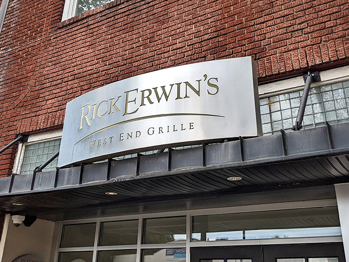 The elegant silver signage against classic brick announces Rick Erwin's West End Grille like a beacon for hungry Greenville locals seeking culinary salvation.