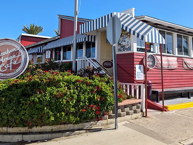 The iconic red exterior with blue-striped awnings stands like a culinary lighthouse on PCH, beckoning hungry travelers with promises of comfort food perfection.