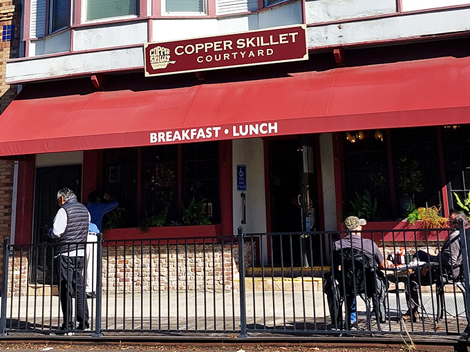 The crimson awning of Copper Skillet Courtyard beckons like a breakfast lighthouse guiding hungry souls through downtown Martinez.