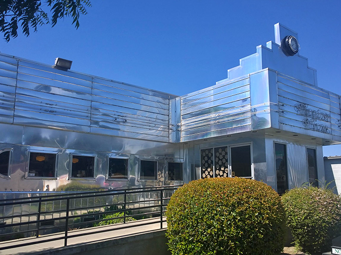 The gleaming stainless steel exterior of Dimples Diner shines like a beacon of hope for hungry travelers. Mid-century modern meets comfort food paradise.