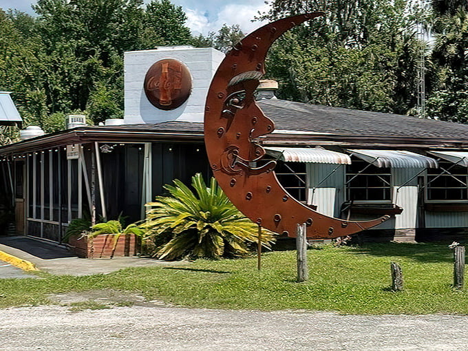 The iconic rusted metal moon sculpture welcomes visitors to The Yearling, where Old Florida charm meets literary history in Hawthorne's backwoods.