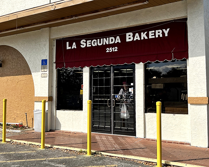 The unassuming storefront with its burgundy awning hides a century of culinary history. Like finding a secret passage to Cuban bread paradise.