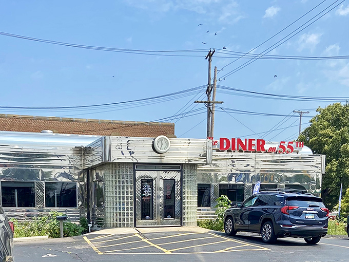The gleaming stainless steel exterior of The Diner on 55th stands as a time capsule of Americana, complete with classic clock and red signage that beckons hungry travelers.