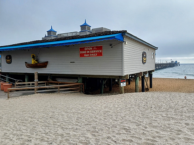 The ultimate beach dining fantasy: a white wooden building perched on stilts above golden sand, with the iconic San Clemente Pier stretching into the Pacific beyond.