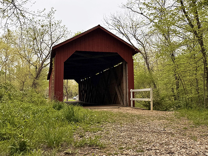 The classic red exterior of Sandy Creek Covered Bridge stands like a portal to the past, complete with white railings guiding visitors into Missouri's rural history.