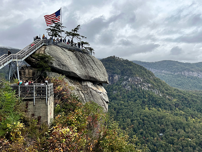 The iconic Chimney Rock juts dramatically from the mountainside, with visitors enjoying panoramic views that make your average selfie spot look like a kiddie pool.