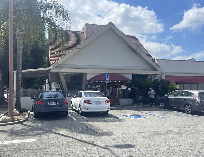 The iconic A-frame exterior stands like a beacon of comfort food, promising sweet salvation under the California sun.