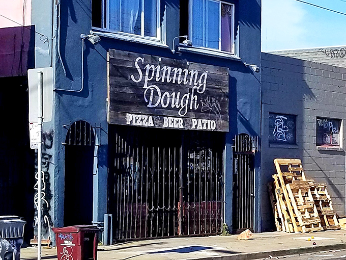 The blue facade of Spinning Dough stands like a culinary speakeasy, its weathered wooden sign promising three essential food groups: pizza, beer, and patio time.
