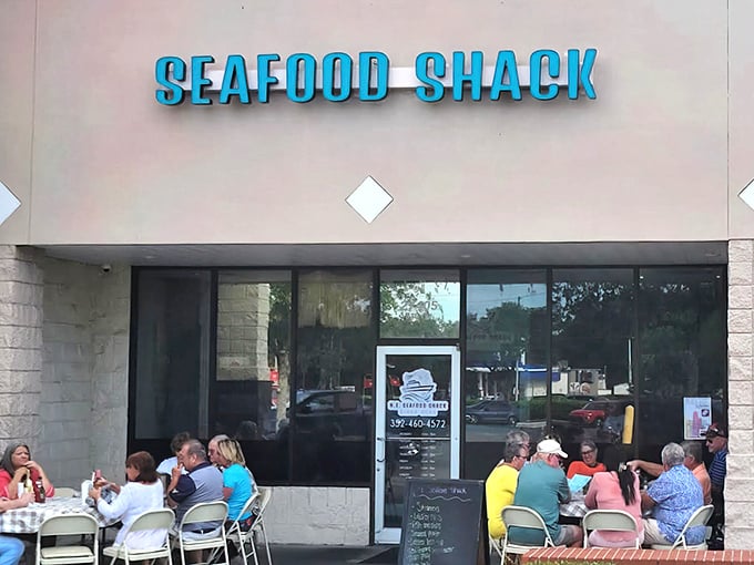 The bright turquoise "SEAFOOD SHACK" sign beckons like a coastal lighthouse, promising maritime treasures within. Those outdoor tables aren't just furniture—they're stages for impending seafood euphoria.