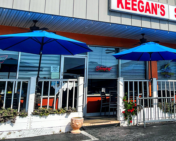 The unassuming exterior of Keegan's Seafood Grille, where those vibrant blue umbrellas hint at the coastal treasures waiting inside.