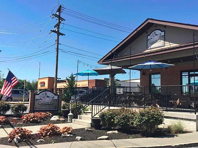 The welcoming exterior of CarterQue BBQ & Grilling Co. stands proudly in Mount Airy, where that American flag and patio practically scream "come get some smoky goodness!"