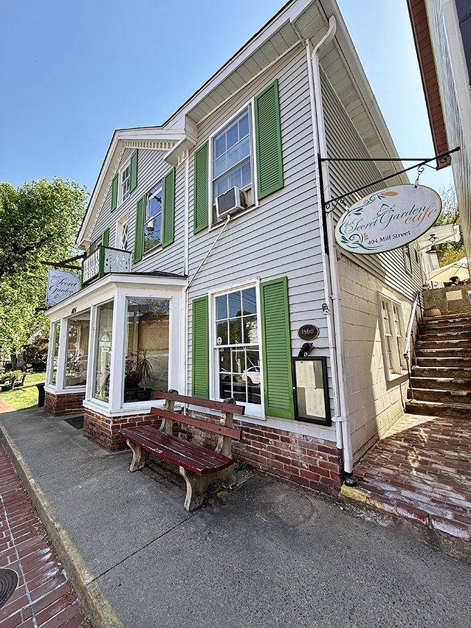 The charming white clapboard exterior with vibrant green shutters beckons like a storybook cottage, promising culinary adventures up those inviting stairs.
