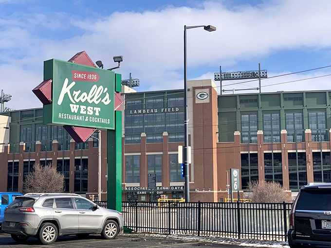 The iconic green Kroll's West sign stands proudly beside Lambeau Field, like a culinary lighthouse guiding hungry Packers fans to burger paradise.