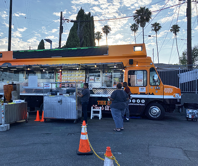 The bright orange beacon of Leo's Tacos Truck stands ready for action, palm trees swaying overhead like nature's own welcome committee.