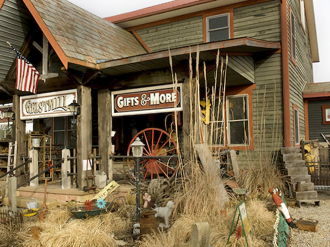 The weathered facade of Grist Mill Antiques beckons like an old friend, complete with wagon wheel and seasonal decor that whispers, "Come in, the past is waiting." 