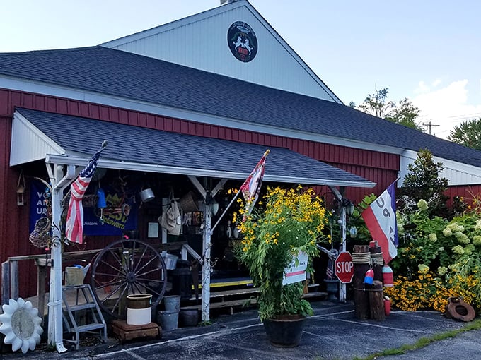 The charming red barn exterior welcomes treasure hunters with its colorful garden display and vintage wagon wheel. A nostalgic portal to the past awaits!