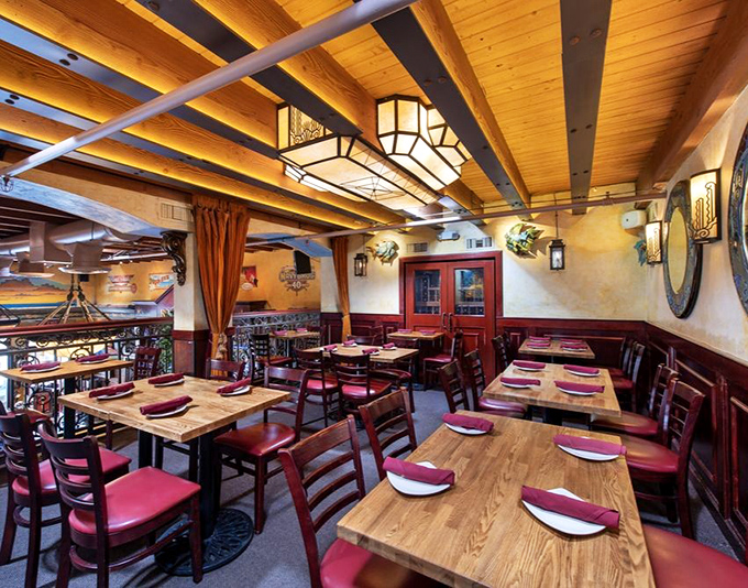 Warm wood beams, lantern lighting, and burgundy accents create a dining room that feels like the world's coziest ship's cabin &ndash; minus the seasickness.