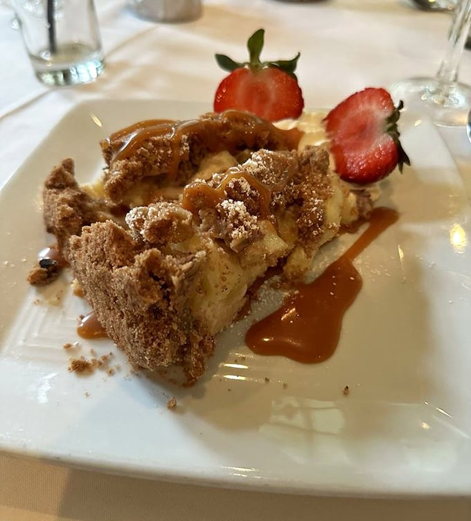 Apple crumb pie that doesn't just satisfy your sweet tooth—it reconciles you with it. Those strawberries and caramel drizzle are just showing off.