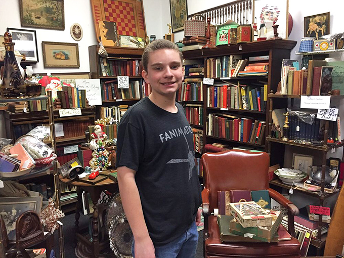 Books stacked from floor to ceiling create the perfect backdrop for treasure hunting. The young browser seems to have found his literary gold mine.